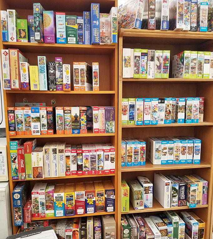 Jigsaw puzzles stacked like promises of rainy day entertainment&mdash;each box a portal to hours of "just one more piece" determination.