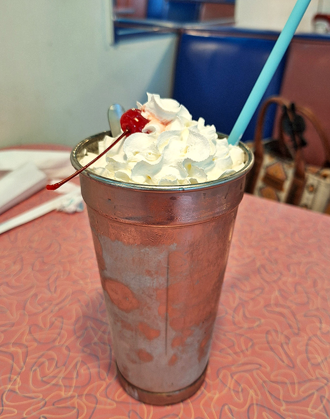 The milkshake arrives in its traditional metal mixing cup, topped with enough whipped cream to qualify as a food group in some particularly enlightened states.