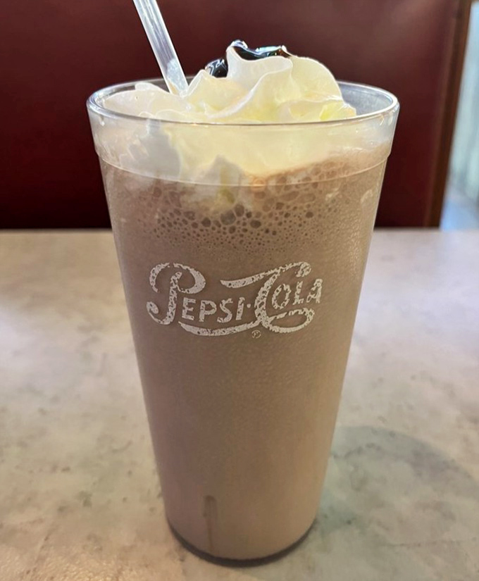 This isn't just a milkshake; it's a time machine in a Pepsi glass. Thick enough to require serious straw commitment, topped with whipped cream that defies gravity.
