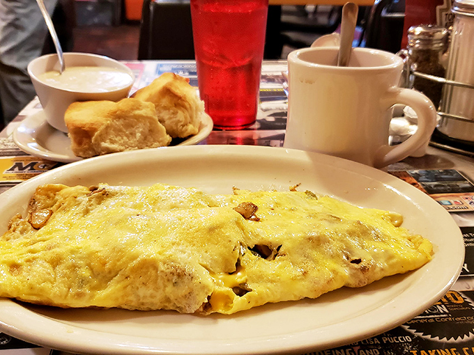 An omelet so generously stuffed it barely folds, accompanied by biscuits that understand their assignment perfectly and a refreshing beverage.