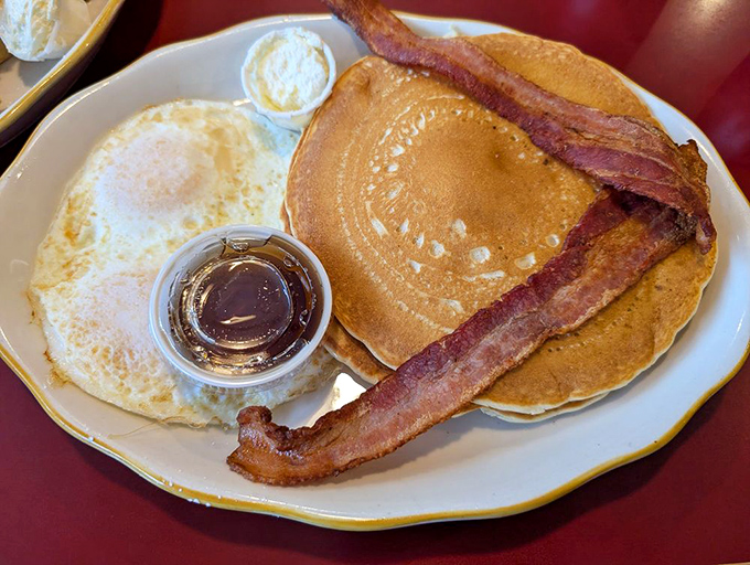 Pancakes and eggs sharing a plate like old friends catching up, with bacon playing the role of delicious chaperone.