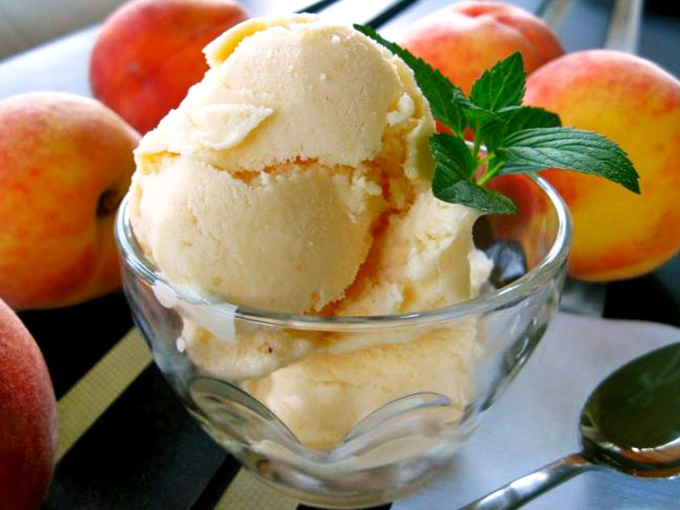 Homemade peach ice cream scooped into a simple glass bowl &ndash; summer captured in dairy form, no complications required.