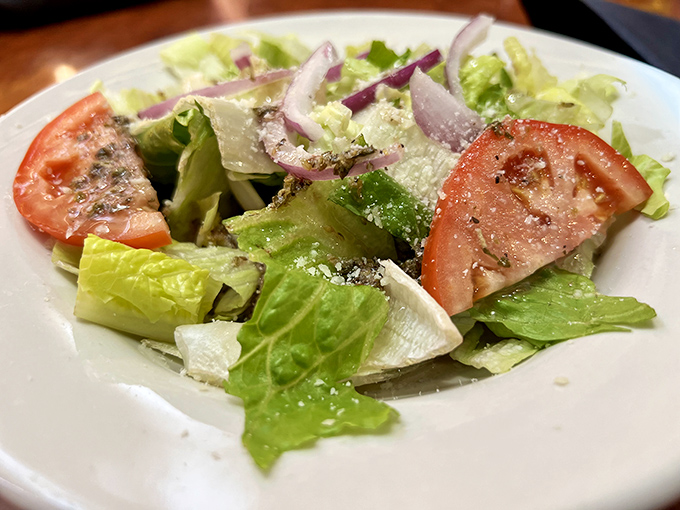 A simple house salad that actually deserves attention &ndash; crisp lettuce, ripe tomatoes, and red onions with just the right dressing.