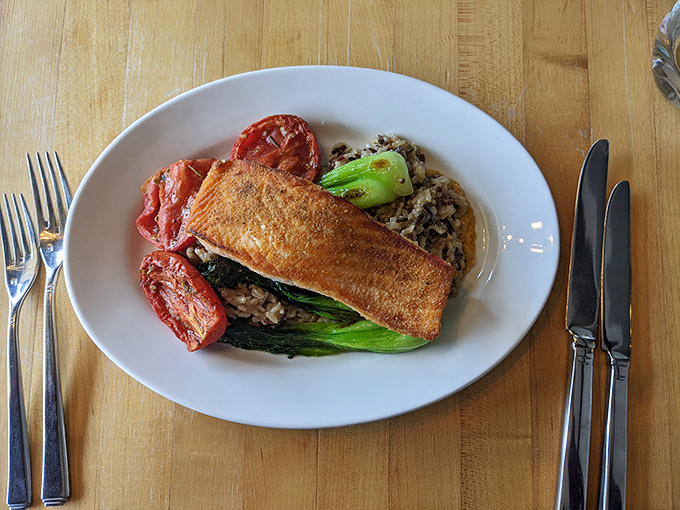 Crispy-skinned salmon perches atop a colorful landscape of grains and roasted tomatoes – proof that healthy can indeed be heavenly.