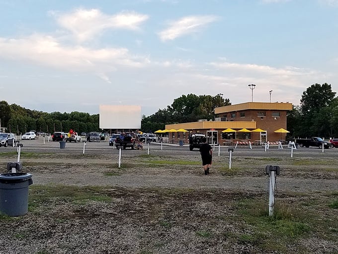 Gravel lot, glowing umbrellas, and cars ready for showtime. Old-school entertainment still holding its own under the open sky.