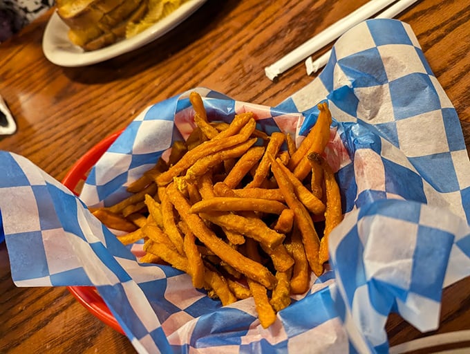 Sweet potato fries served in a checkered basket&mdash;crispy, orange treasures that somehow let you pretend you're making a healthier choice.