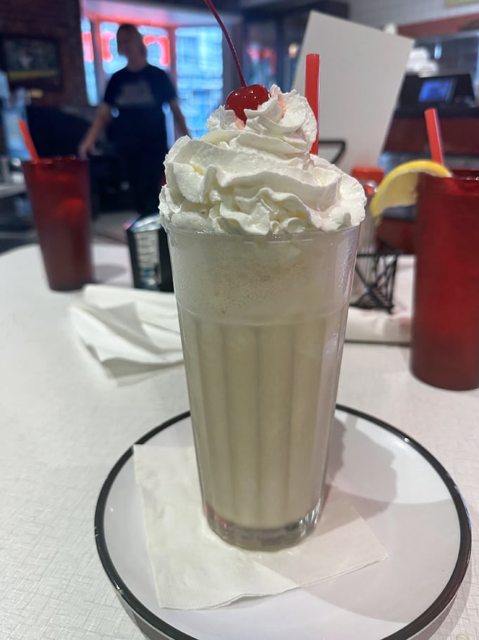 The vanilla milkshake arrives like a cloud in a glass, topped with a mountain of whipped cream that dares you not to smile.