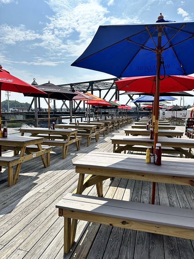 The sprawling deck at Bill's Seafood, where wooden picnic tables await hungry visitors. Colorful umbrellas dot the scene like confetti.