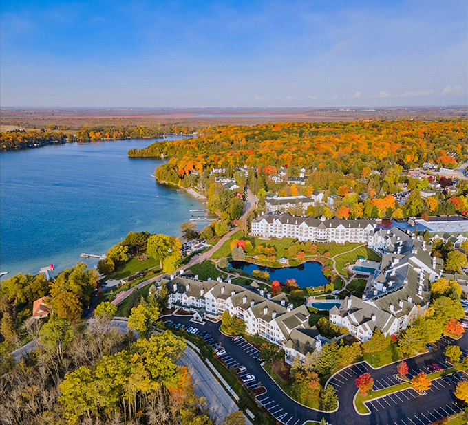 Nature's color wheel gone wild! Elkhart Lake's resort kingdom rises from fall's fiery forest like a white-walled sanctuary where leaf-peeping meets luxury.
