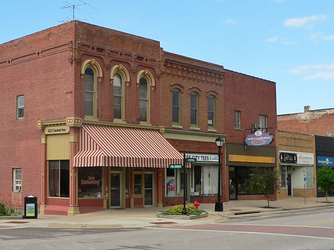 Red brick storefronts with striped awnings create the perfect small-town shopping district atmosphere.