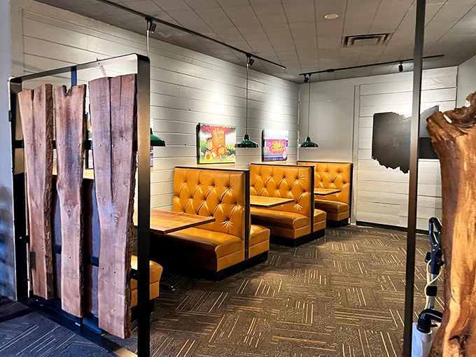 Mustard-yellow booths invite lingering conversations, while rustic wood dividers create intimate spaces for plotting your next pizza selection.