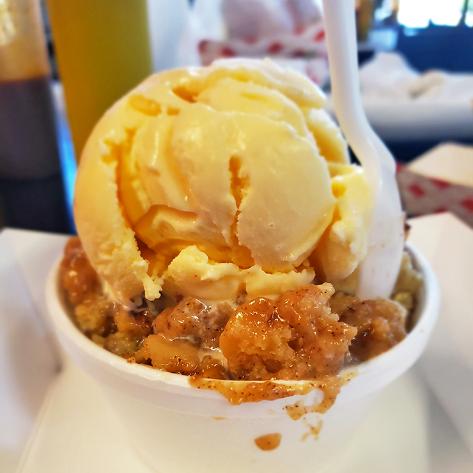 Peach cobbler crowned with ice cream melting into warm, cinnamon-spiced fruit below. The dessert equivalent of a perfect Texas sunset.
