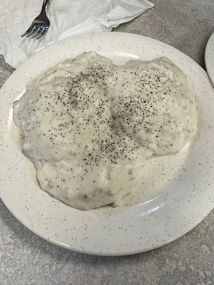 Beneath that pepper-speckled blanket of creamy gravy lies a biscuit that's about to experience the culinary equivalent of a warm hug.