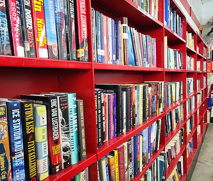 The vibrant red bookshelves hold literary worlds waiting to be rediscovered, from bestsellers to forgotten gems.