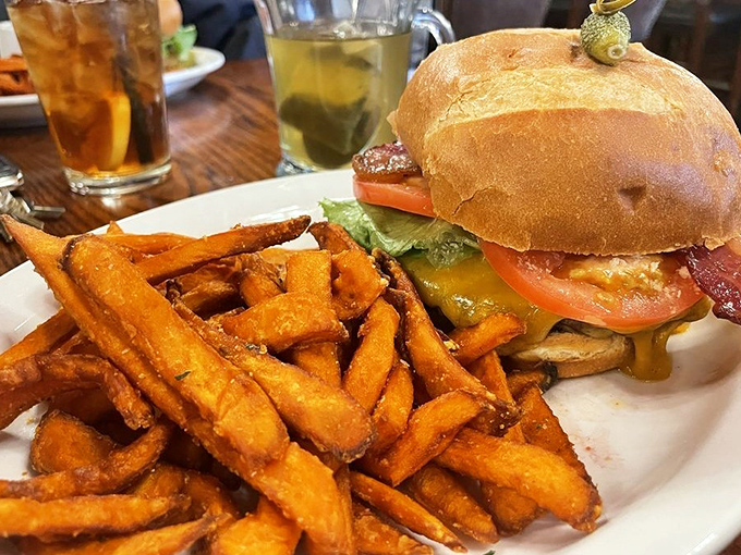 A burger that requires both hands and several napkins, flanked by sweet potato fries that somehow manage to be both crispy and pillowy.