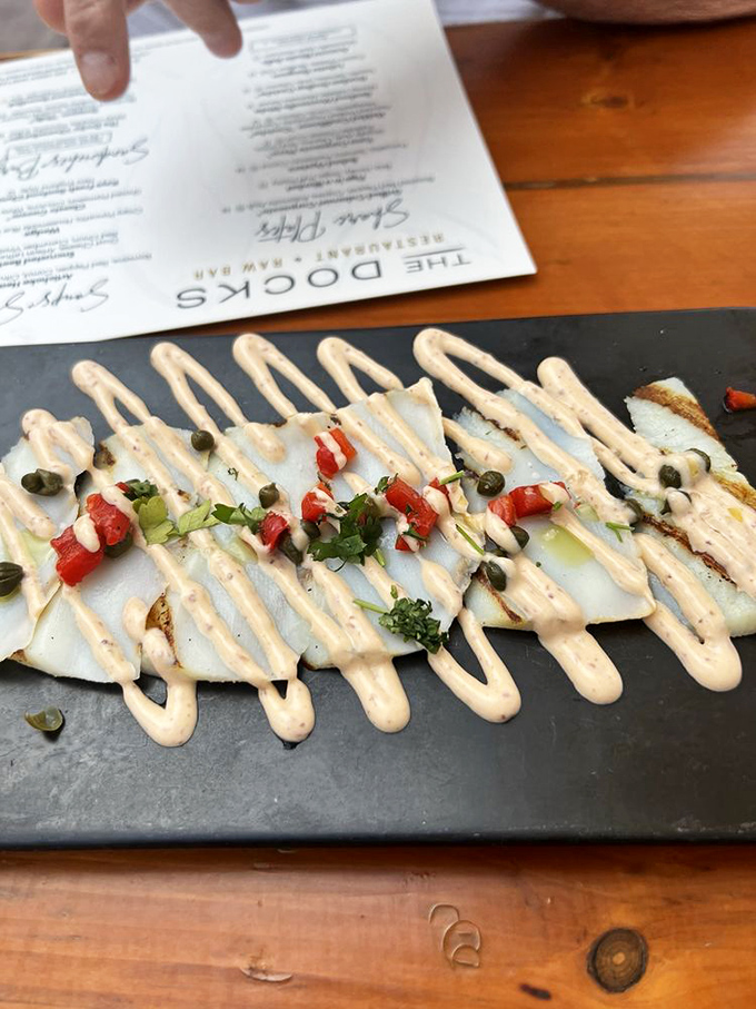 Sliced so thin you could read the menu through it. This elegant calamari carpaccio gets dressed up with a zigzag of creamy sauce and bright garnishes.