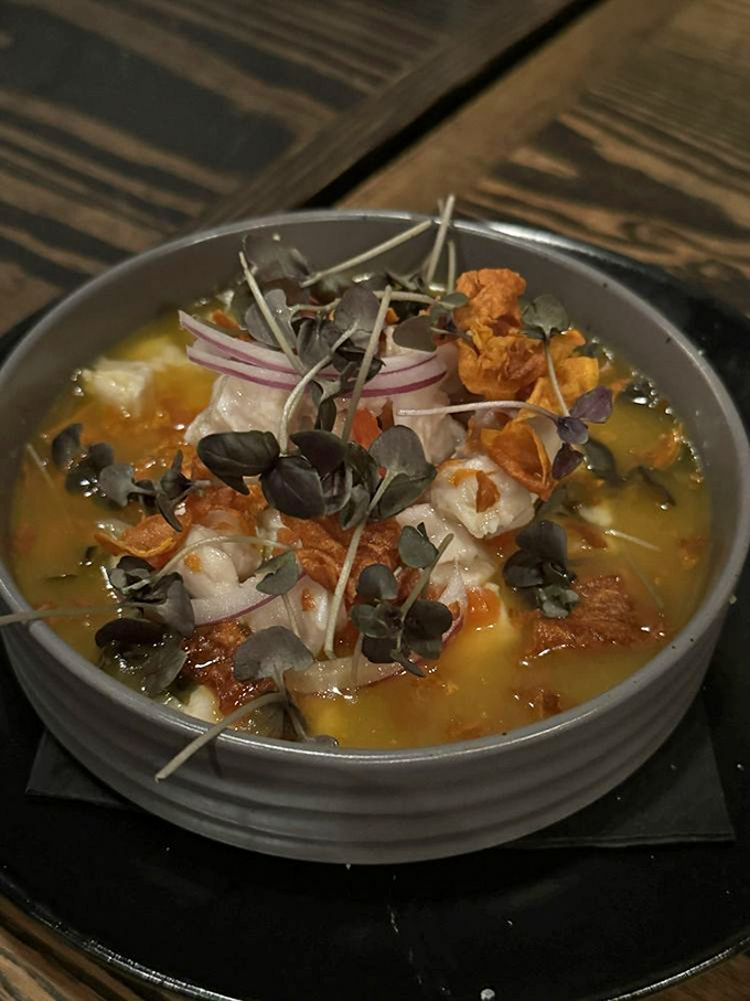 A bowl of sunshine disguised as seafood soup. Those crispy garnishes add texture to what's essentially a warm hug in liquid form.