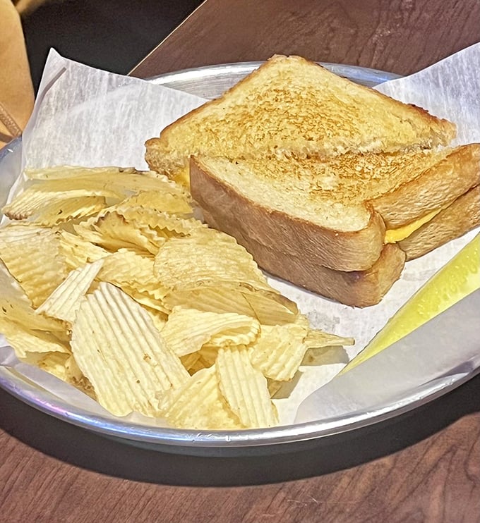 The humble grilled cheese&mdash;elevated from childhood memory to adult comfort. Paired with chips, it's nostalgia served on a metal plate.