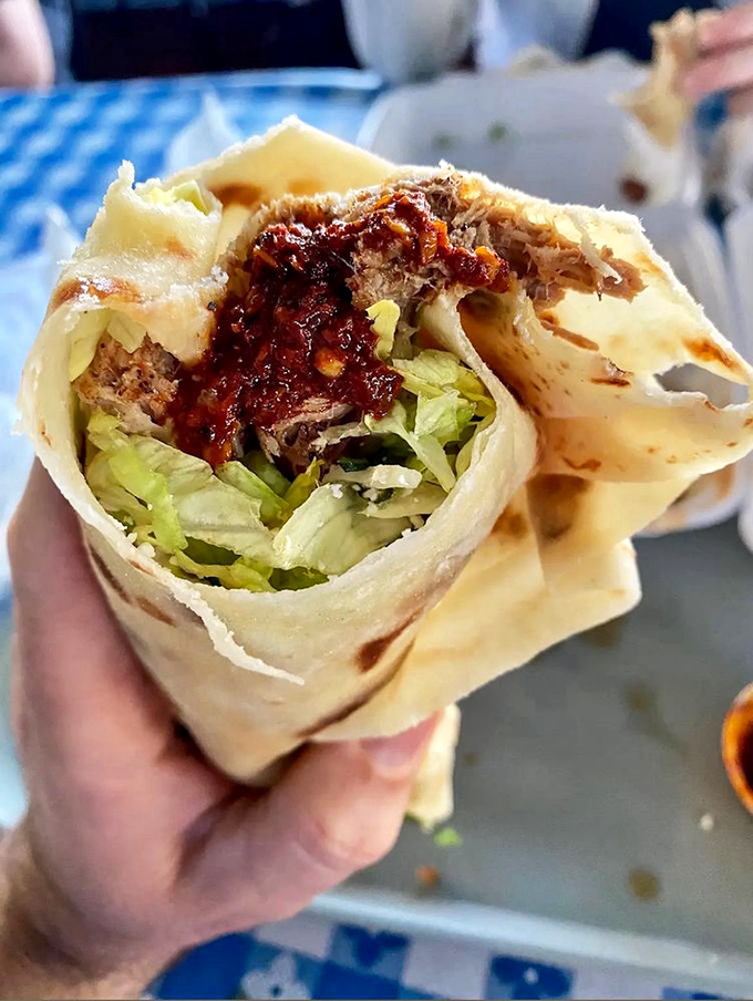 The burrito cross-section reveals the architectural marvel within&mdash;layers of meat, lettuce, and that vibrant salsa creating a handheld masterpiece that demands to be savored.