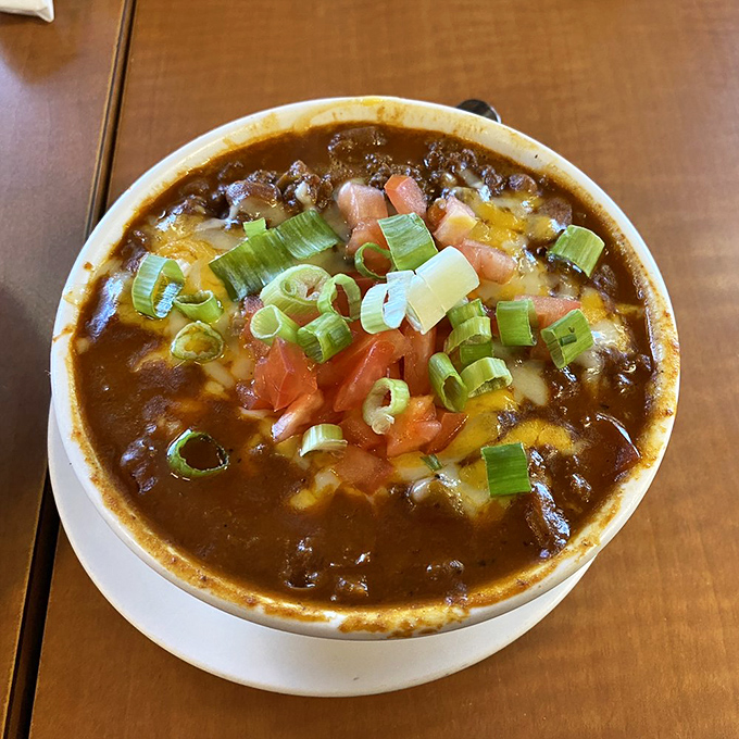 A bowl of chili that doesn't care what time of day it is – topped with enough cheese and green onions to make you forget about dessert.