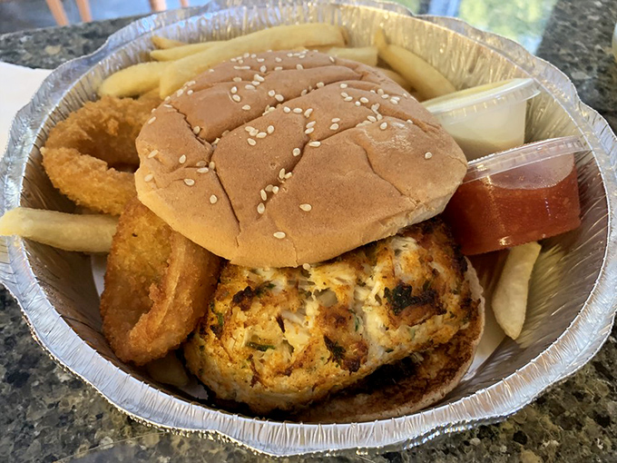 The crab cake sandwich arrives like edible architecture &ndash; golden-crusted Maryland blue crab elevated to sandwich royalty with a side of crispy rings.
