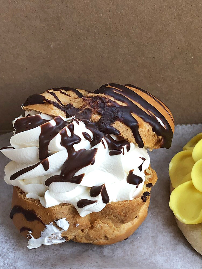 Behold: a cream puff that defies physics. Cloud-like whipped cream nestled in pastry, drizzled with chocolate &ndash; dessert's answer to world peace.