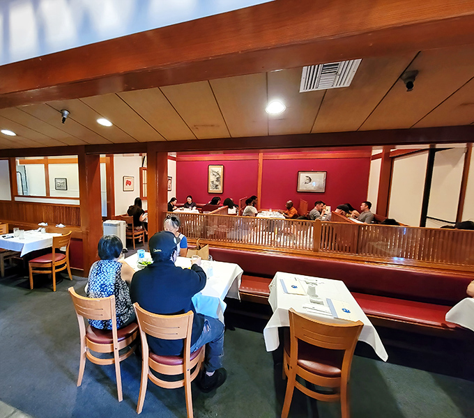The dining room balances elegance with comfort, where red banquettes and wooden dividers create intimate spaces for serious sushi appreciation.