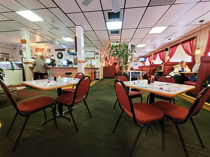 Red chairs pop against green carpet in this dining area where conversations flow as freely as the gravy on your meatloaf.