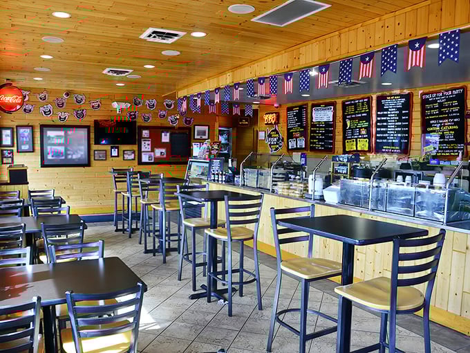 American flags hang proudly above a counter where serious barbecue business happens daily. The wooden interior feels like a cabin that specializes in meat.
