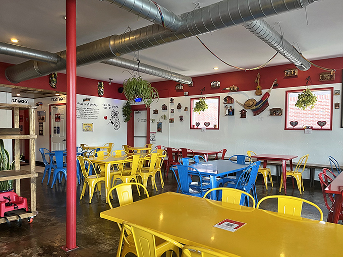 The dining room feels like an artist's palette come to life, where primary-colored chairs pop against industrial elements. Even the ceiling pipes look intentional here.