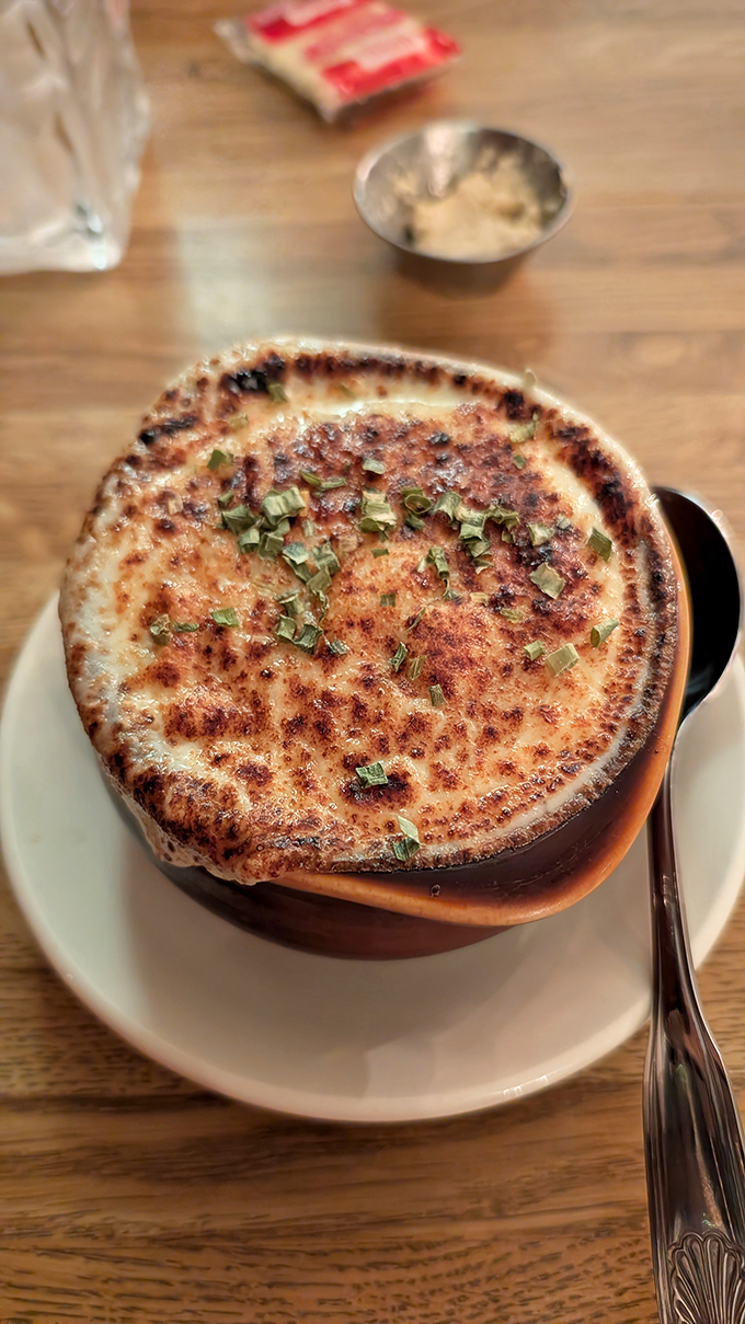 French onion soup wearing its traditional cheese cap like a crown&mdash;a bubbling cauldron of comfort that demands to be broken into.
