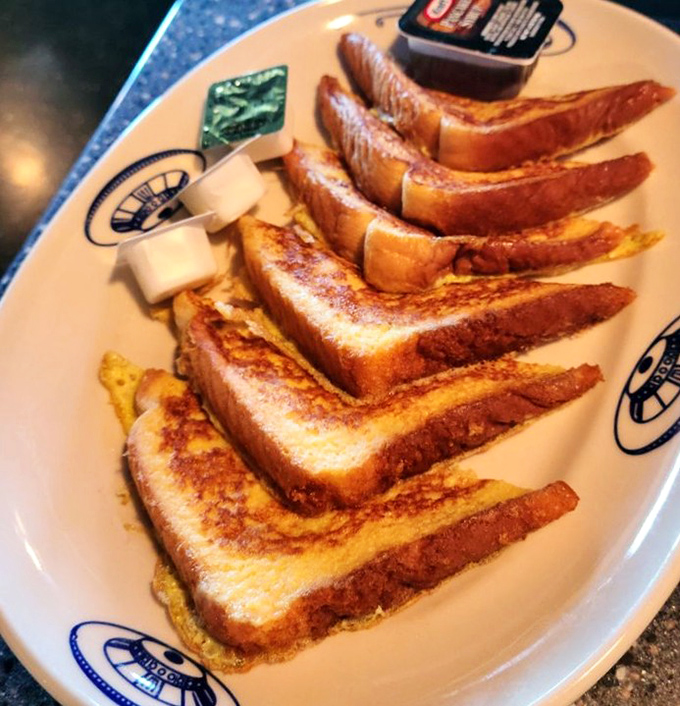 French toast stacked with military precision. Golden-brown slices that have clearly mastered the art of the perfect egg-to-bread ratio.