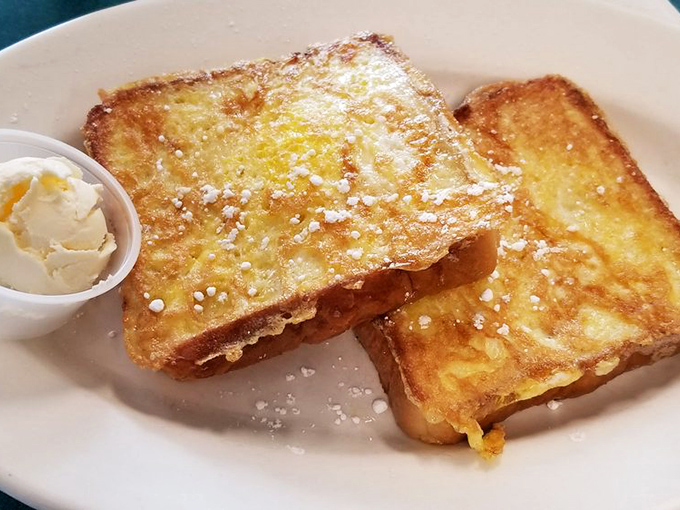 French toast that doesn't need a social media strategy – just the perfect golden crust, a dusting of powdered sugar, and a side of butter that means business.