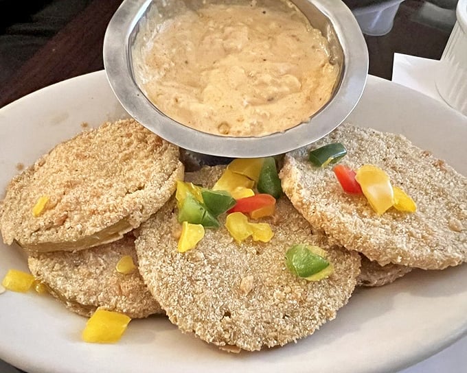 Fried green tomatoes—tangy slices of Southern ingenuity transformed into golden discs of delight, served with what appears to be a remoulade worth fighting over.