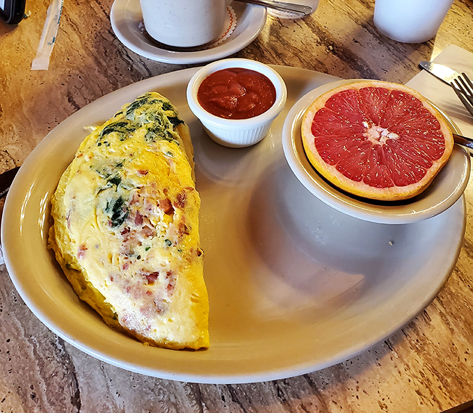 A fluffy omelette that's practically bursting with fillings, served with a grapefruit half that adds a perfect citrus counterpoint.