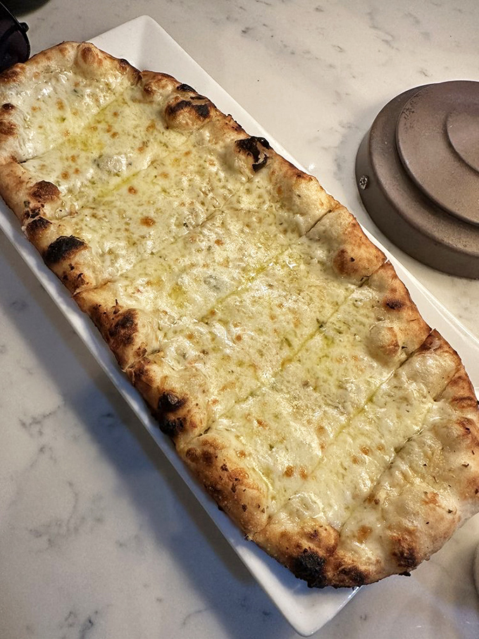 Garlic bread elevated to art form: a canvas of perfectly charred dough painted with garlic-infused oils and a dusting of cheese.