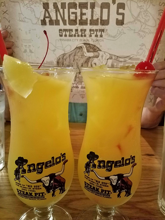 Angelo's signature drinks arrive in souvenir glasses featuring Big Gus himself, turning refreshment into a take-home memory.