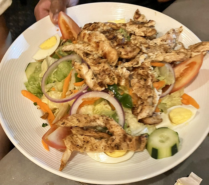 A grilled chicken salad that proves seafood restaurants can handle land-based proteins with equal finesse. Those red onions mean business.