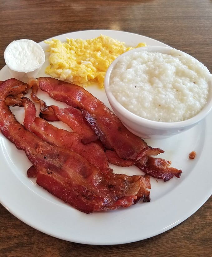 The breakfast trinity: crispy bacon, fluffy eggs, and creamy grits&mdash;proof that sometimes the simplest combinations create the most profound satisfaction.