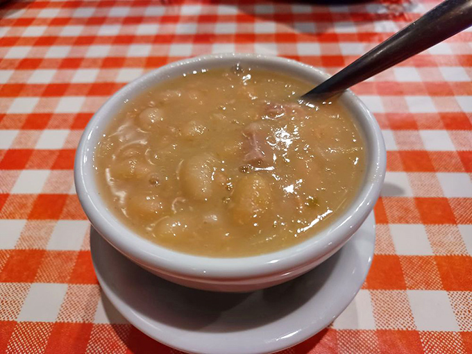A steaming bowl of ham and bean soup on a checkered tablecloth &ndash; the kind of simple perfection that warms you from the inside out.