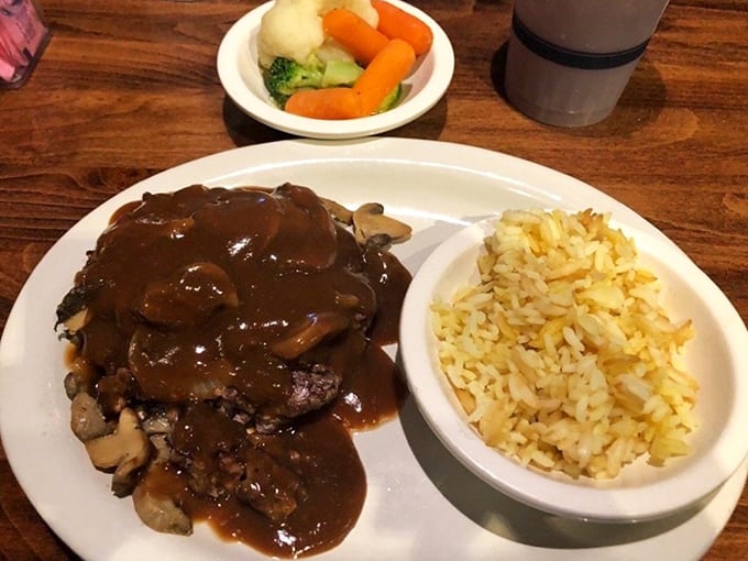 The hamburger steak arrives smothered in rich mushroom gravy, paired with perfectly seasoned rice&mdash;proof that comfort food transcends all culinary boundaries.