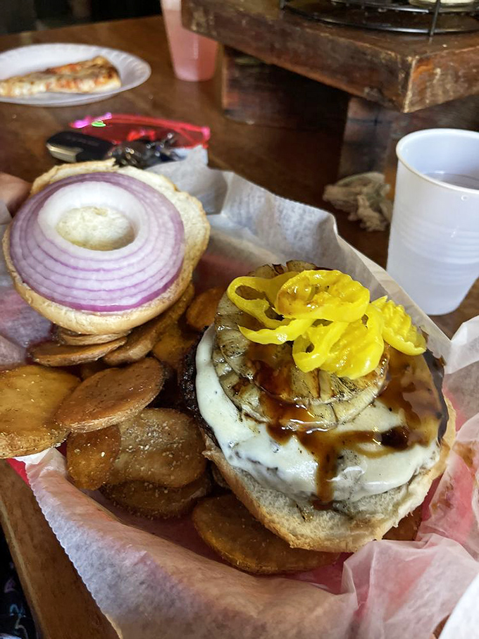 This burger isn't just topped&mdash;it's architecturally enhanced with a tower of grilled onions, peppers, and mushrooms that defy gravity.