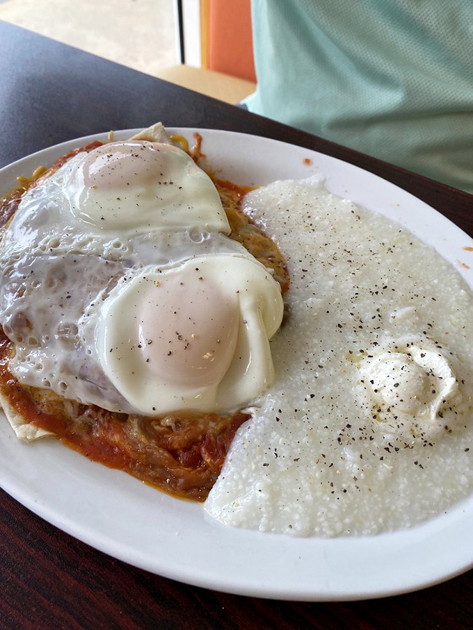 Eggs perched atop a spicy tomato sauce with a side of creamy grits &ndash; breakfast that doesn't just wake you up, it gives you a reason to live.
