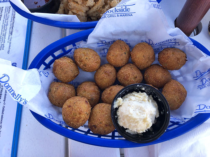 Hushpuppies huddle together in their basket, golden sentinels guarding a kingdom of creamy dipping sauce.