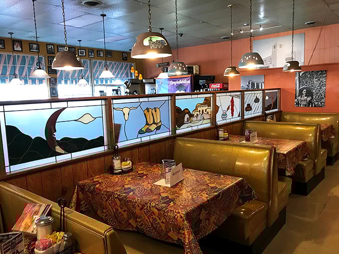 Southwestern-inspired stained glass dividers transform ordinary booths into intimate dining nooks bathed in warm, golden light.