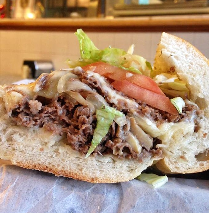 Cross-section evidence of sandwich mastery: perfectly seasoned beef, melted cheese, and fresh vegetables. This is what food photographers dream about at night.
