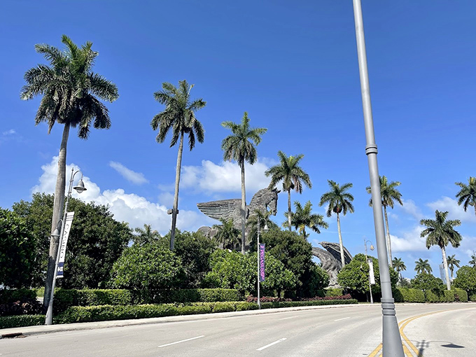 Royal palm trees stand at attention, creating a majestic boulevard worthy of the legendary creatures they frame.