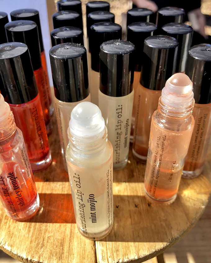 Artisanal lip oils lined up like tiny potions, promising to transform chapped reality into glossy possibility.