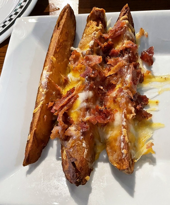 Potato wedges living their best life, blanketed in melted cheese and bacon bits—proof that sometimes the side dish deserves to be the main event.