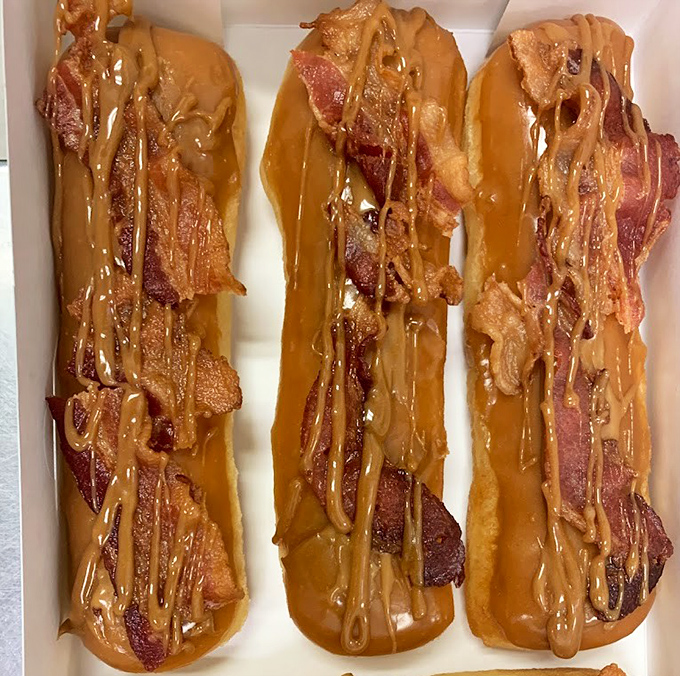 Three strips of bacon lounging on maple bars like they're on vacation in Donut Paradise.